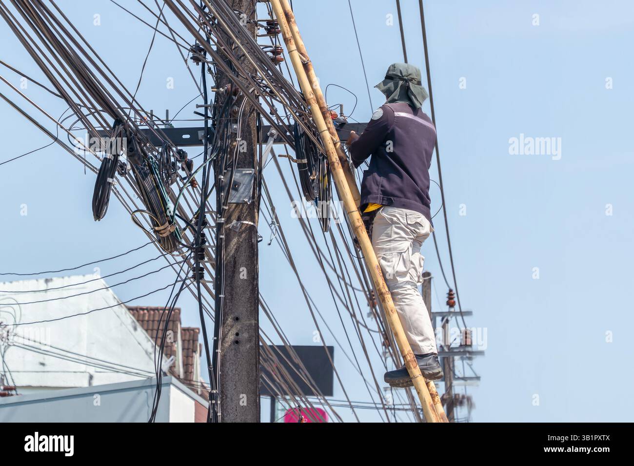 A utility worker is engaged in repairs on power lines in an urban area ...
