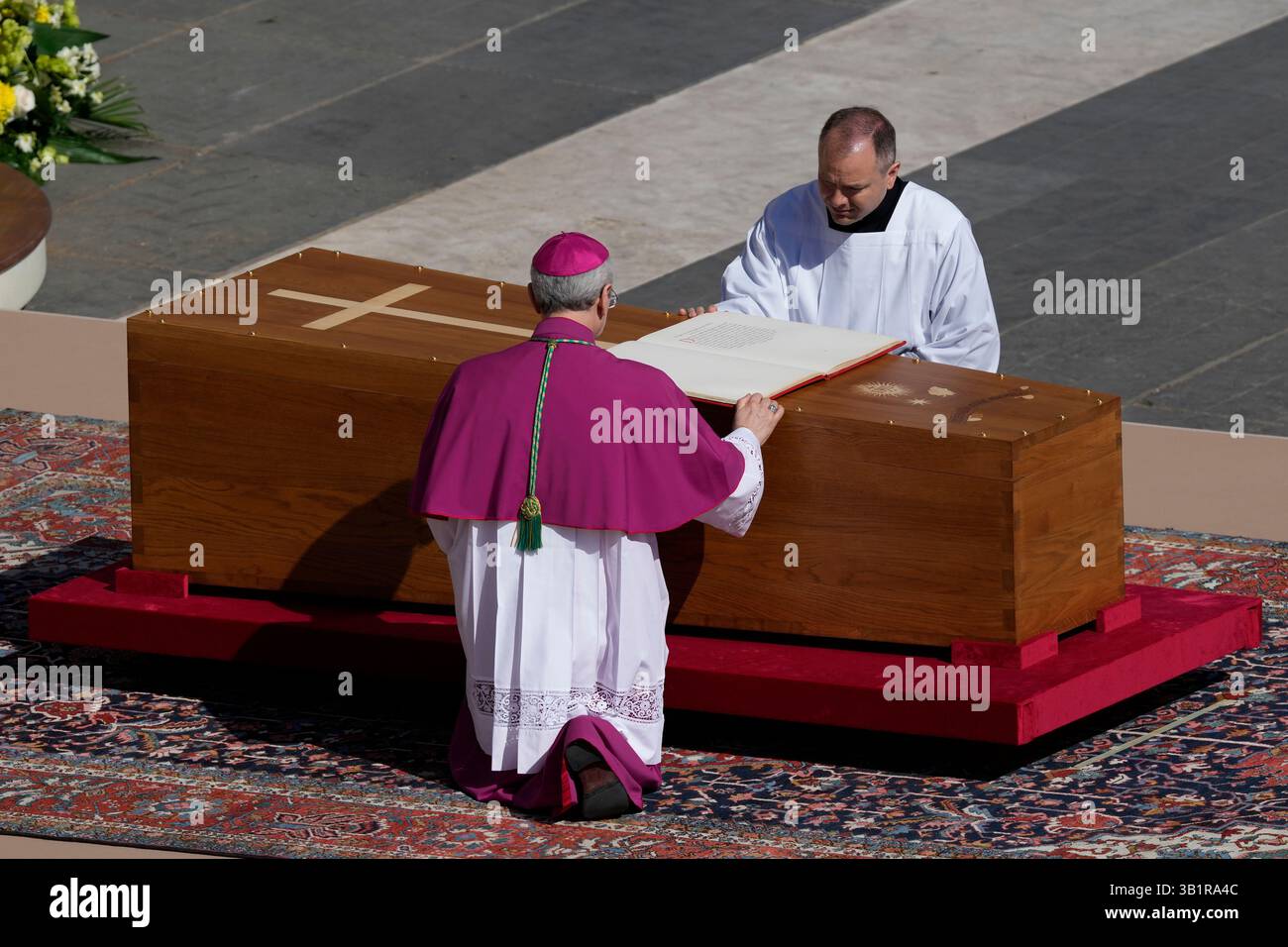 Archbishop Diego Giovanni Ravelli, back to camera, kneels by the coffin ...