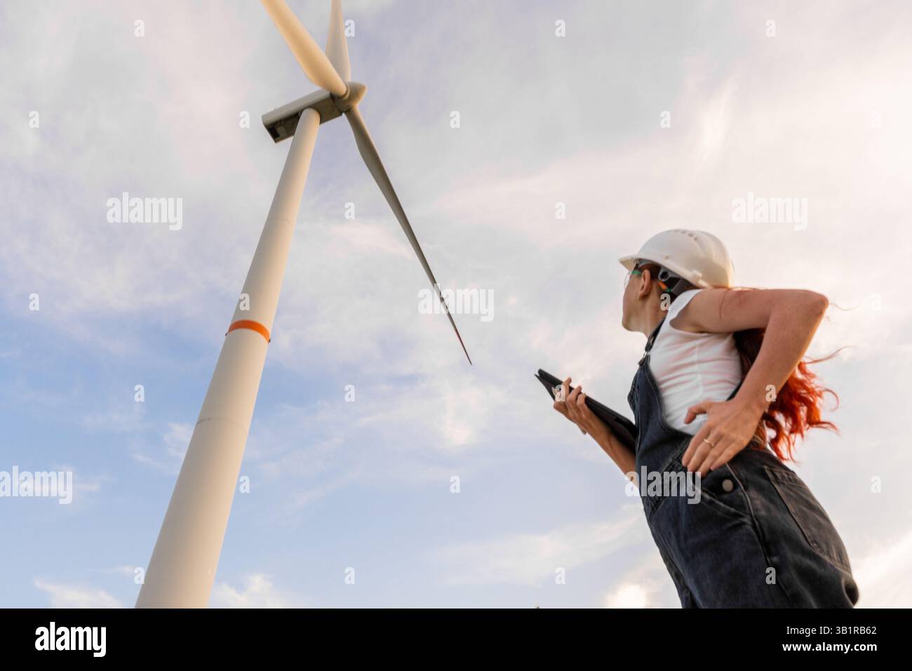A young female engineer studies a wind turbines design, analyzing its ...
