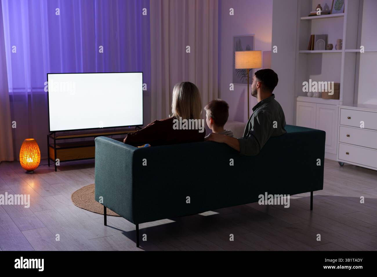 Happy family watching tv together at home in evening Stock Photo - Alamy