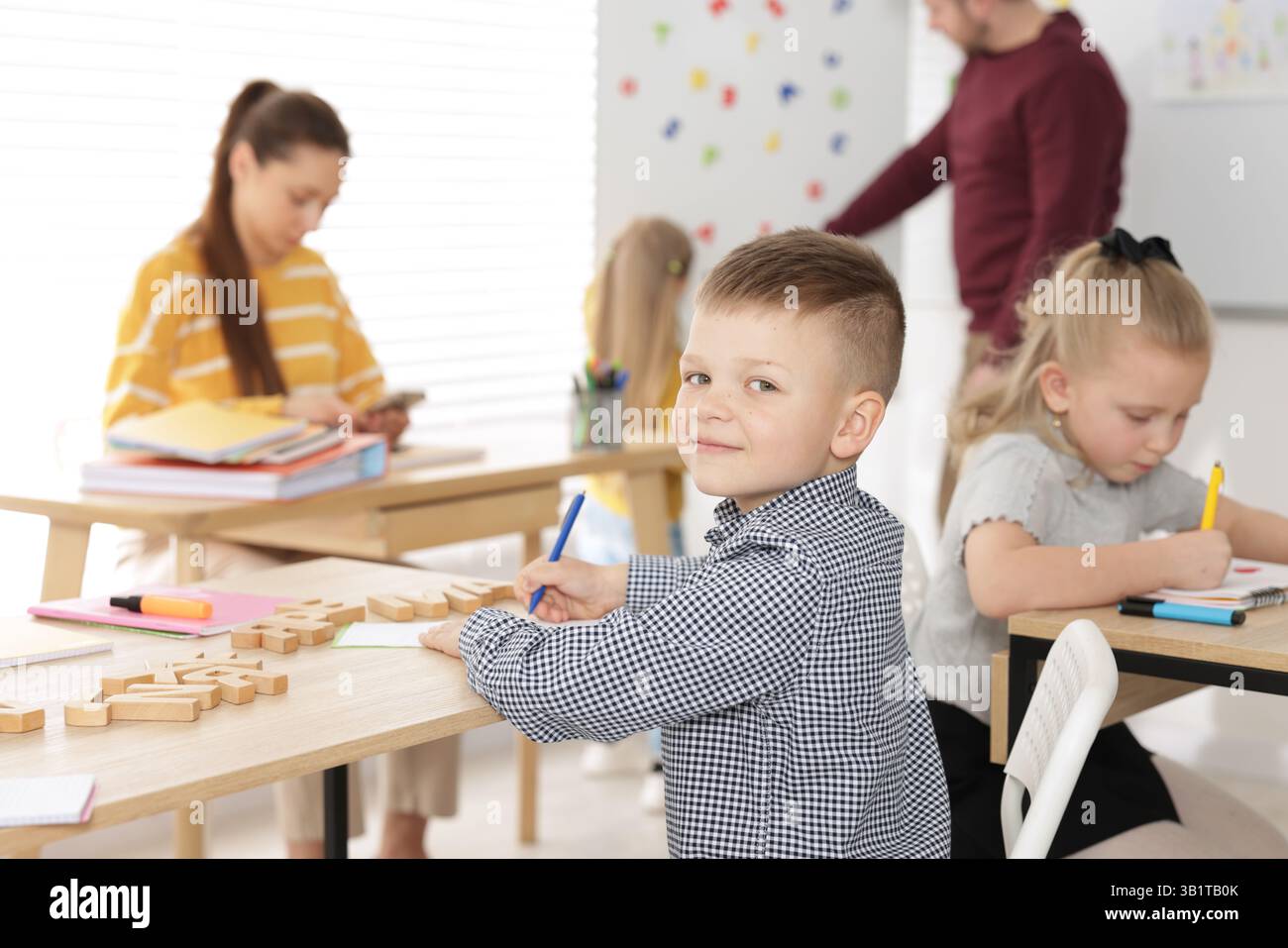 Cute boy learning letters at desk in school Stock Photo - Alamy