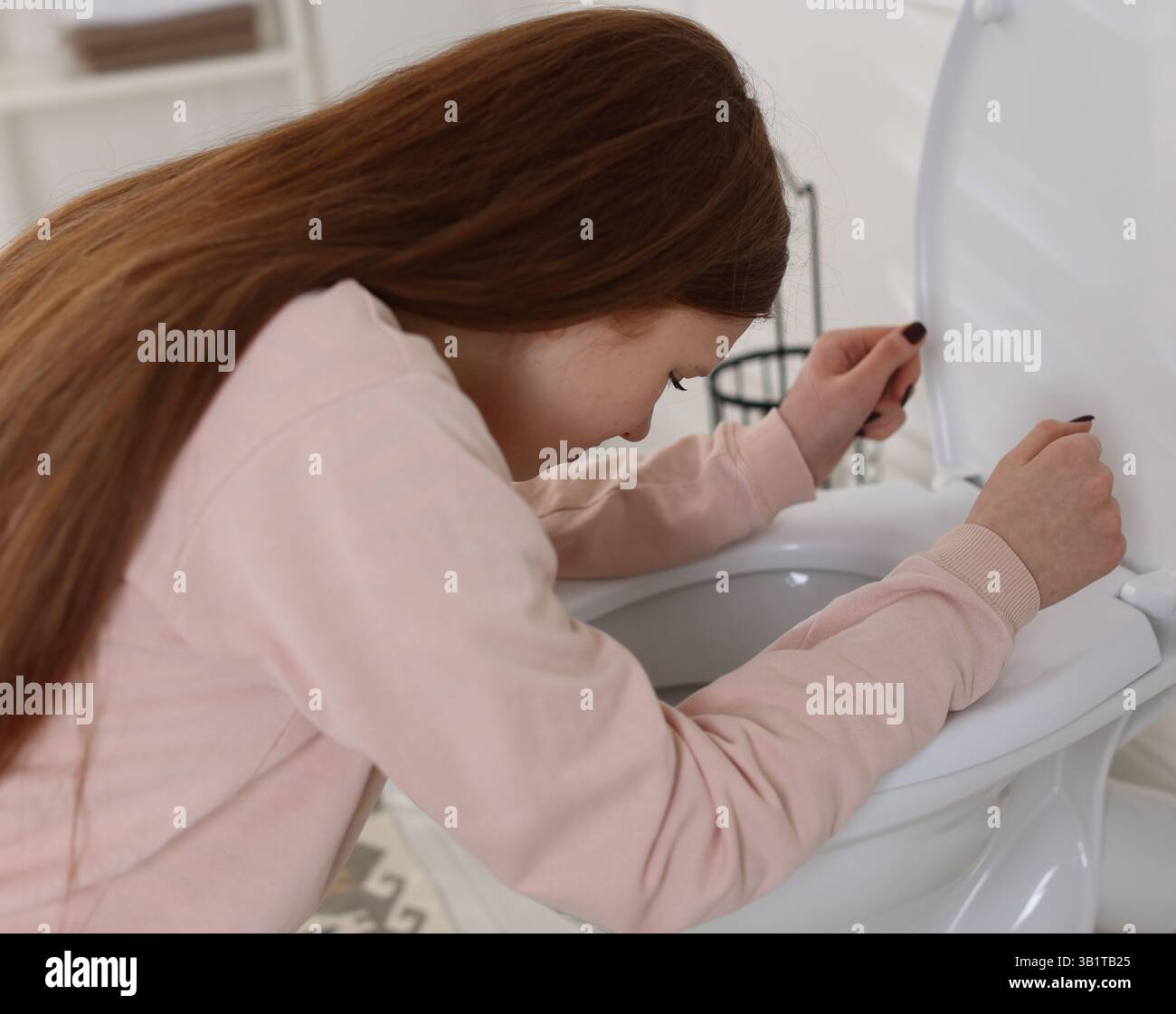 Teenage girl suffering from nausea over toilet bowl in bathroom ...