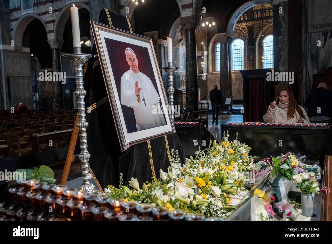 A person lighting a candle near a photo of Pope Francis at Westminster ...