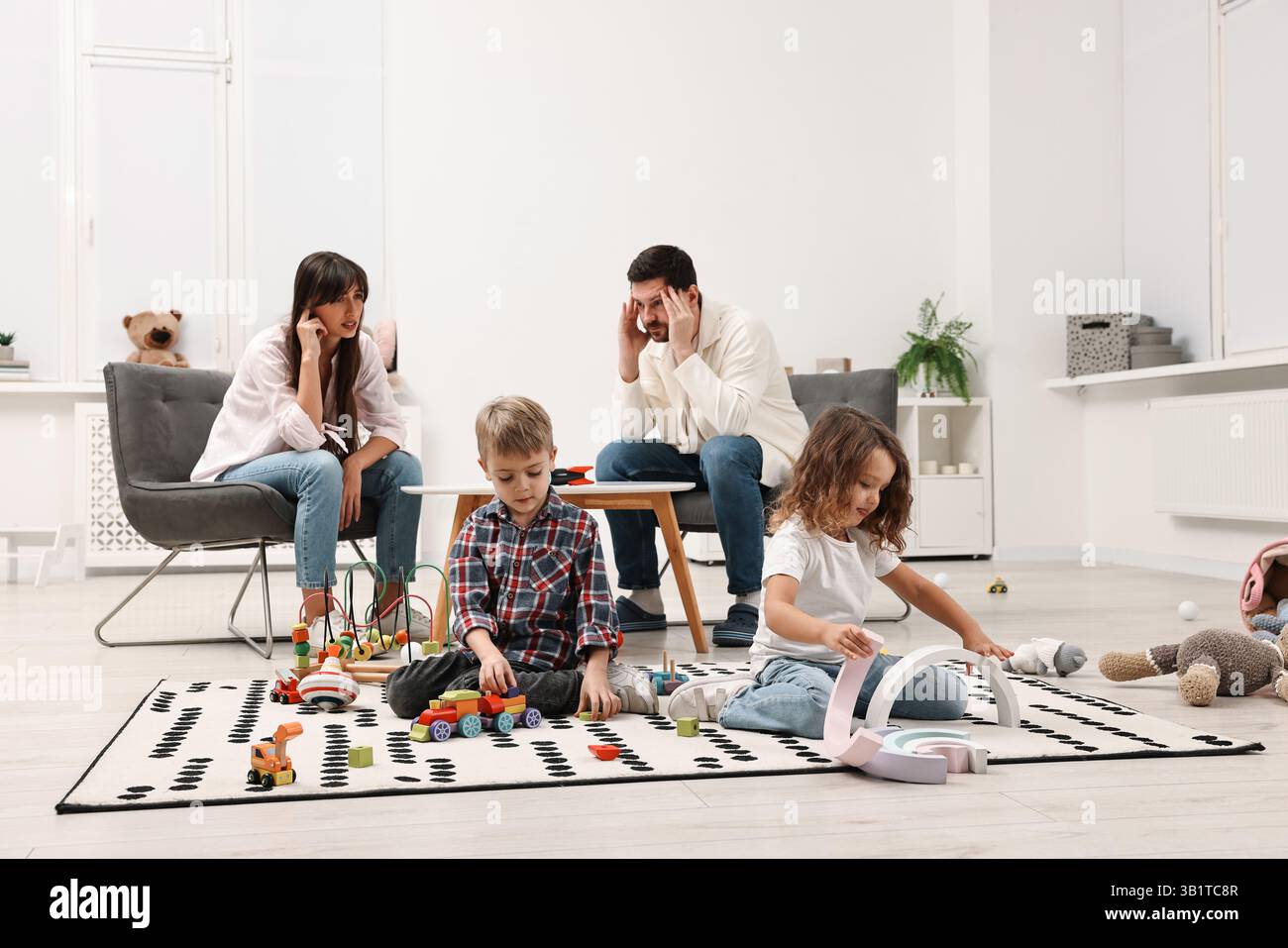 Hyperactive children playing and their overwhelmed parents at home ...