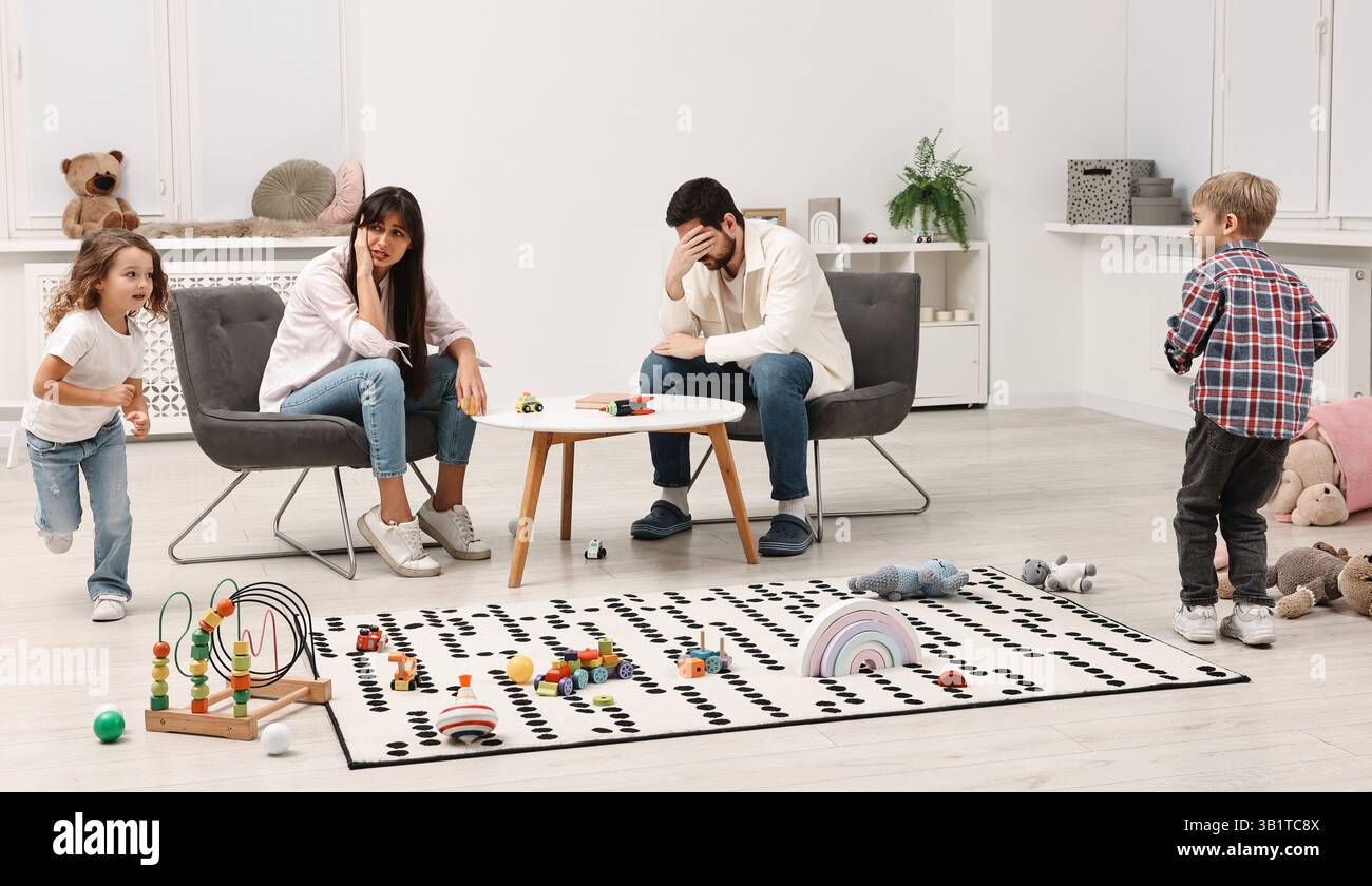 Hyperactive children playing and their overwhelmed parents at home ...