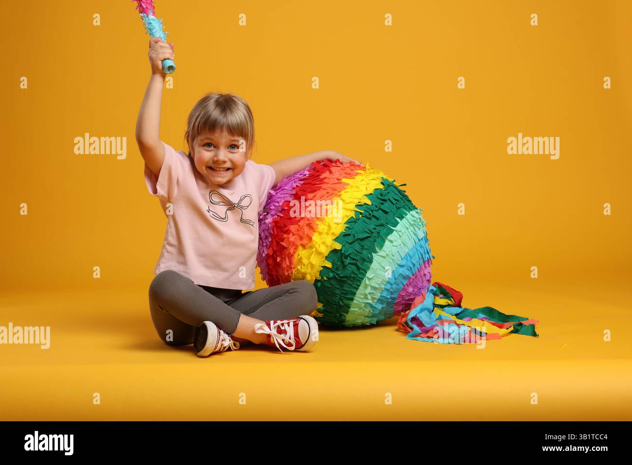Happy girl with bright pinata and stick on orange background Stock ...