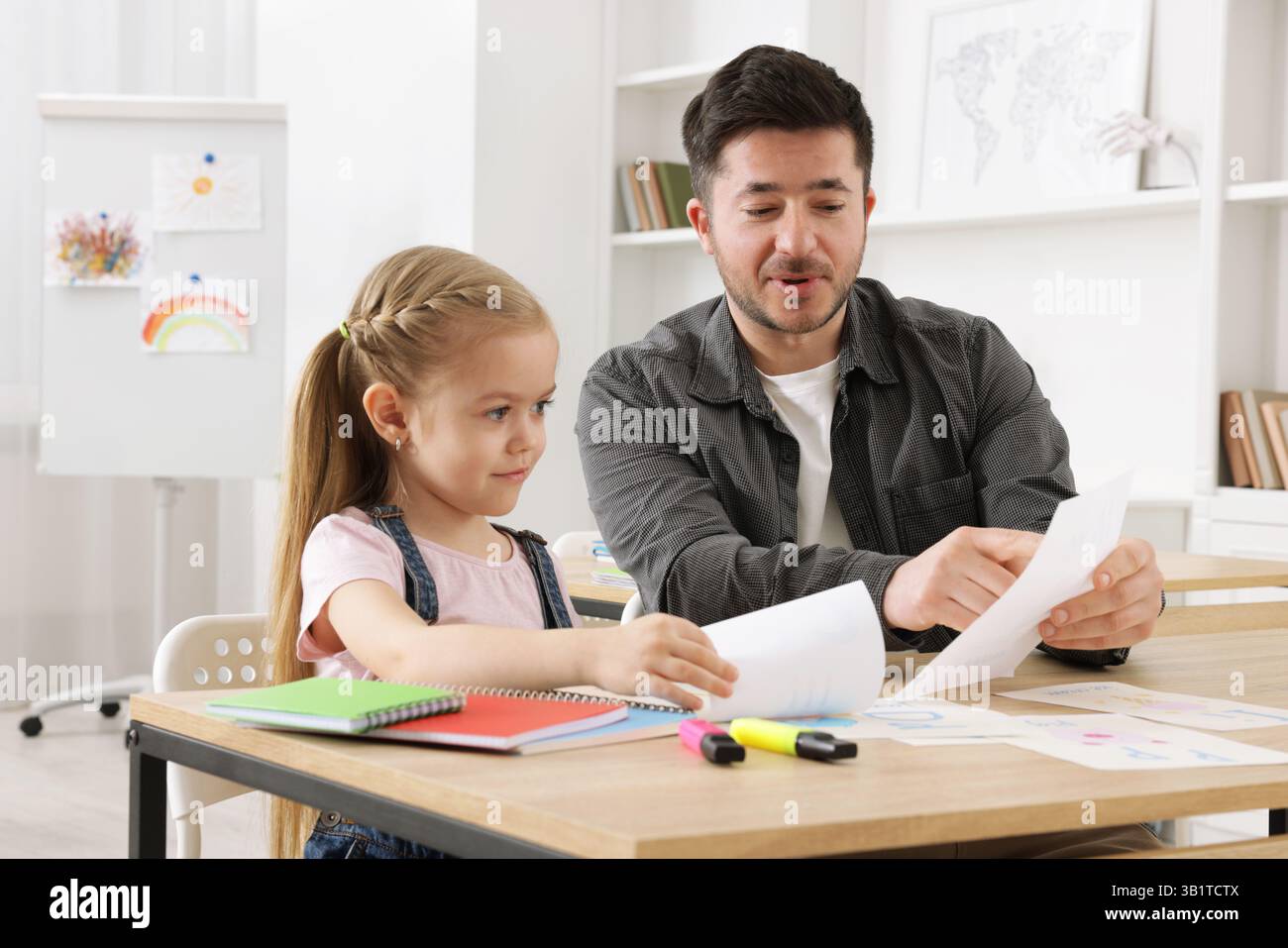 Teacher having lesson with little girl at desk indoors Stock Photo - Alamy
