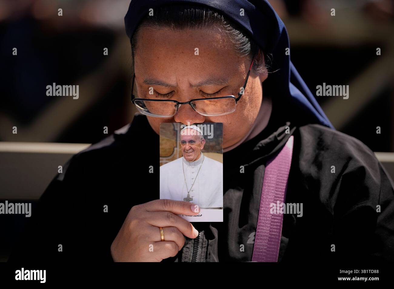 A nun holds a photo of Pope Francis while attending his funeral in St ...