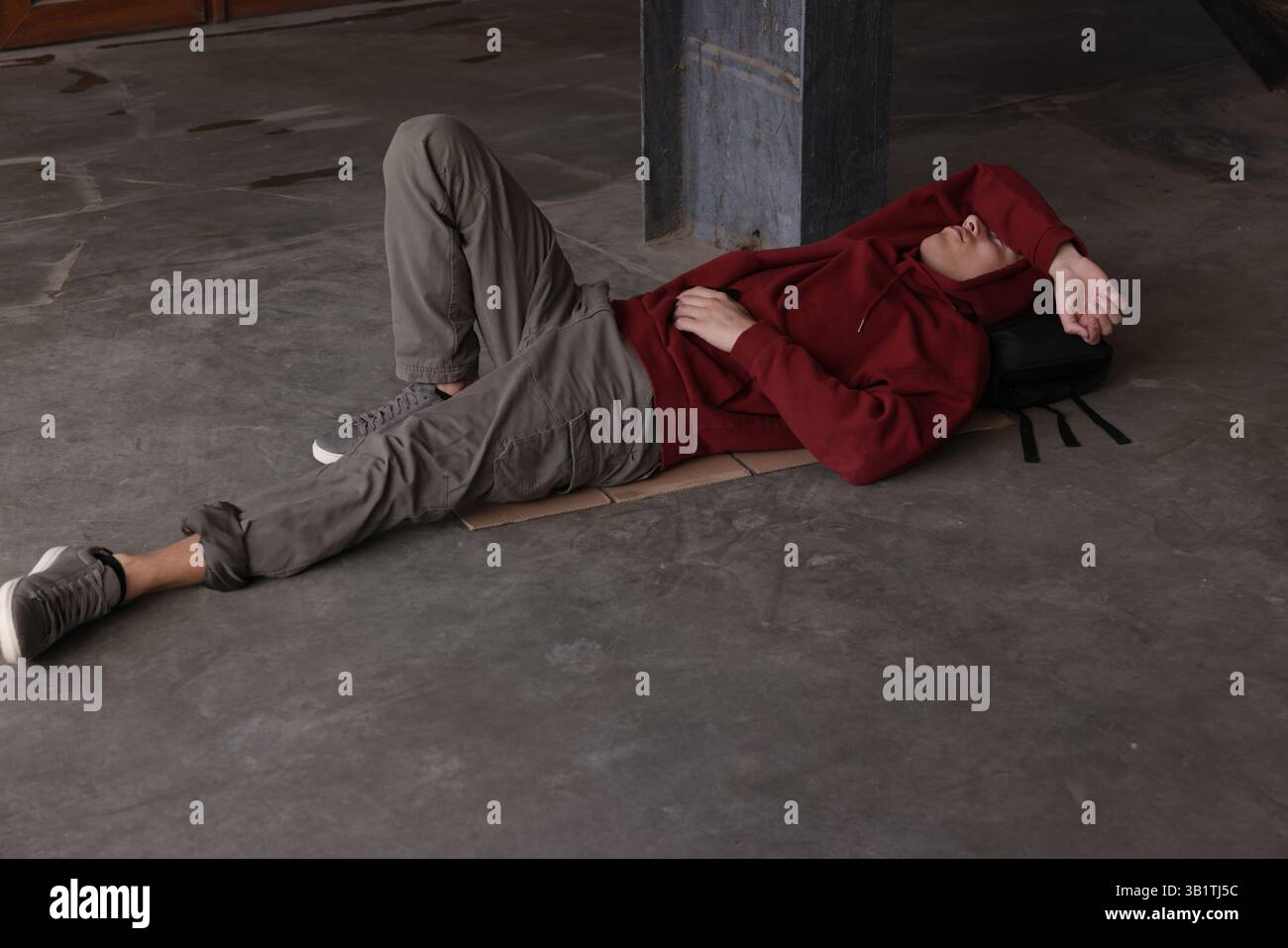 Homeless man lying on concrete floor outdoors Stock Photo - Alamy