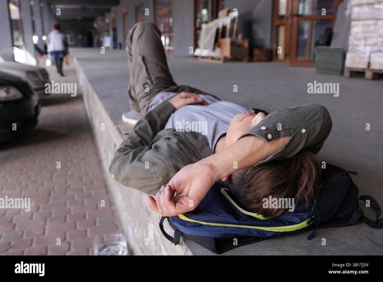 Homeless man lying on concrete floor outdoors Stock Photo - Alamy