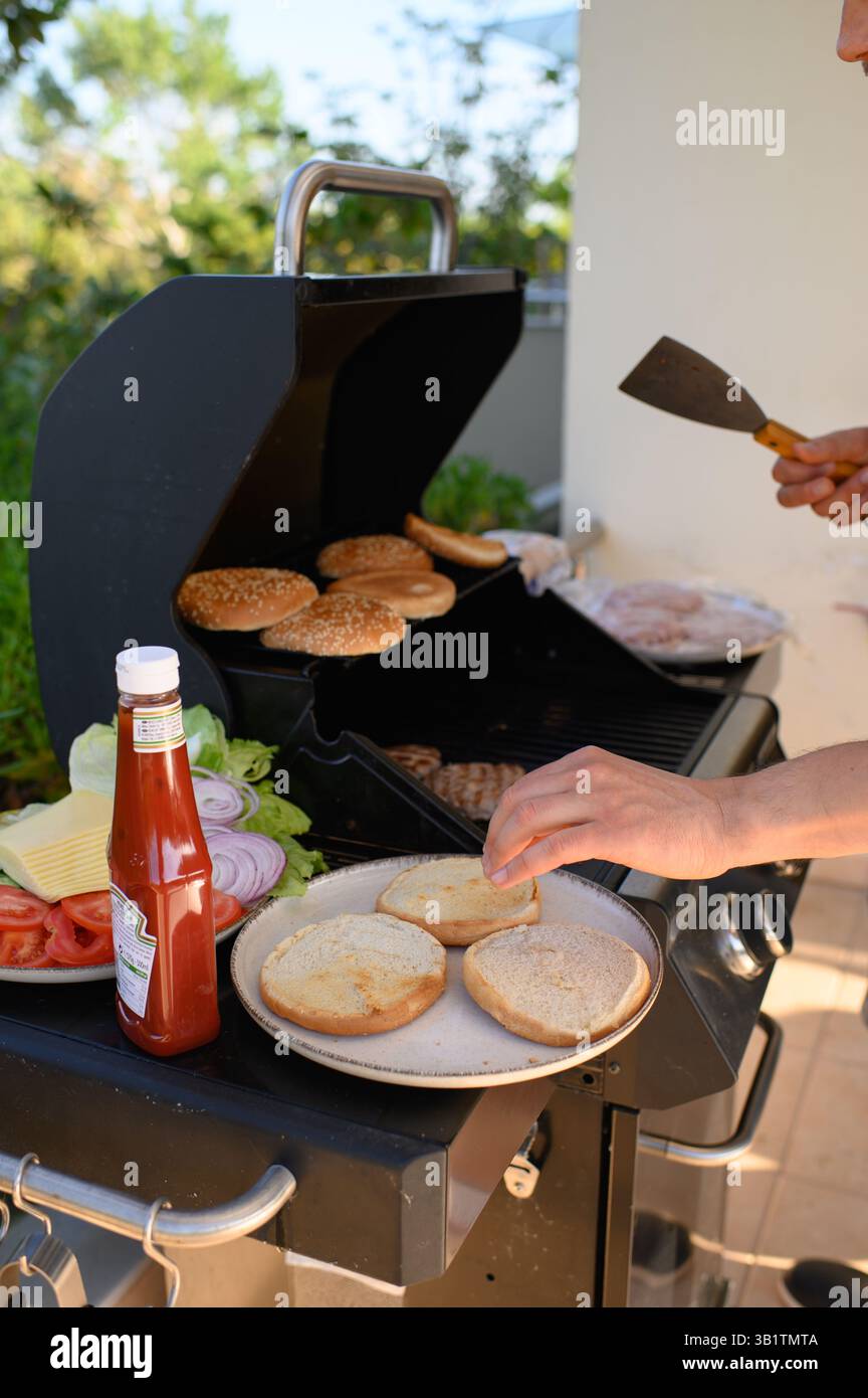 Hands assembling juicy burger patties on buns Stock Photo - Alamy