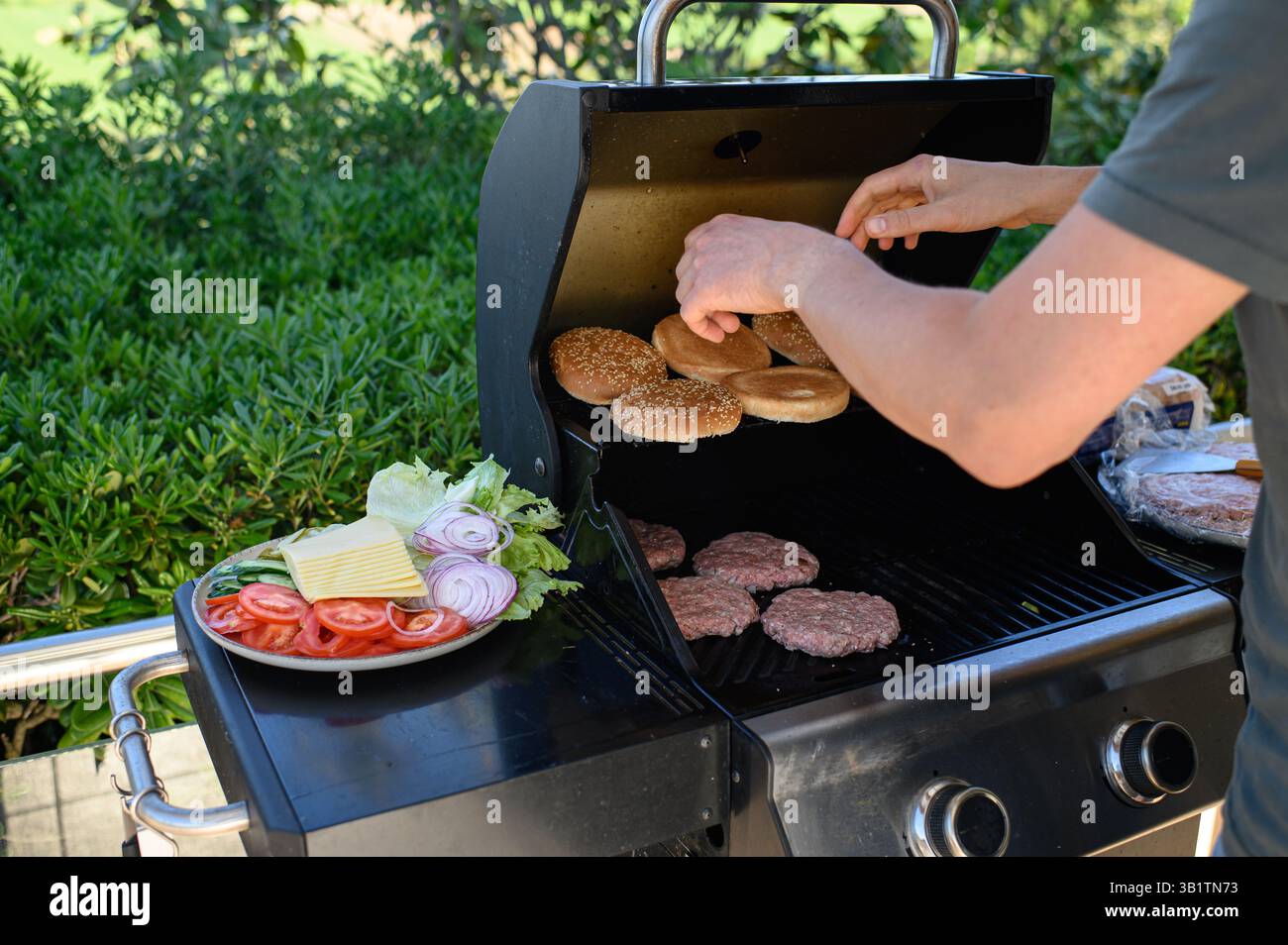 Hands assembling juicy burger patties on buns Stock Photo - Alamy