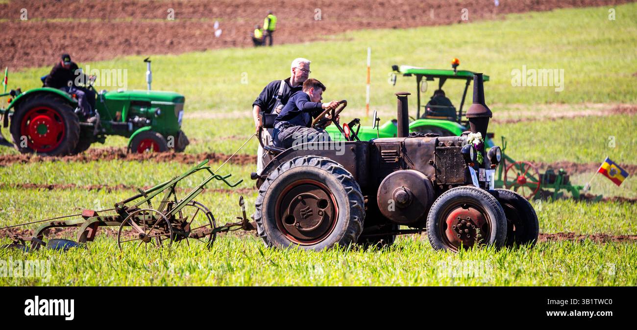 Goddin, Germany. 26th Apr, 2025. Historic tractors drive across a field ...