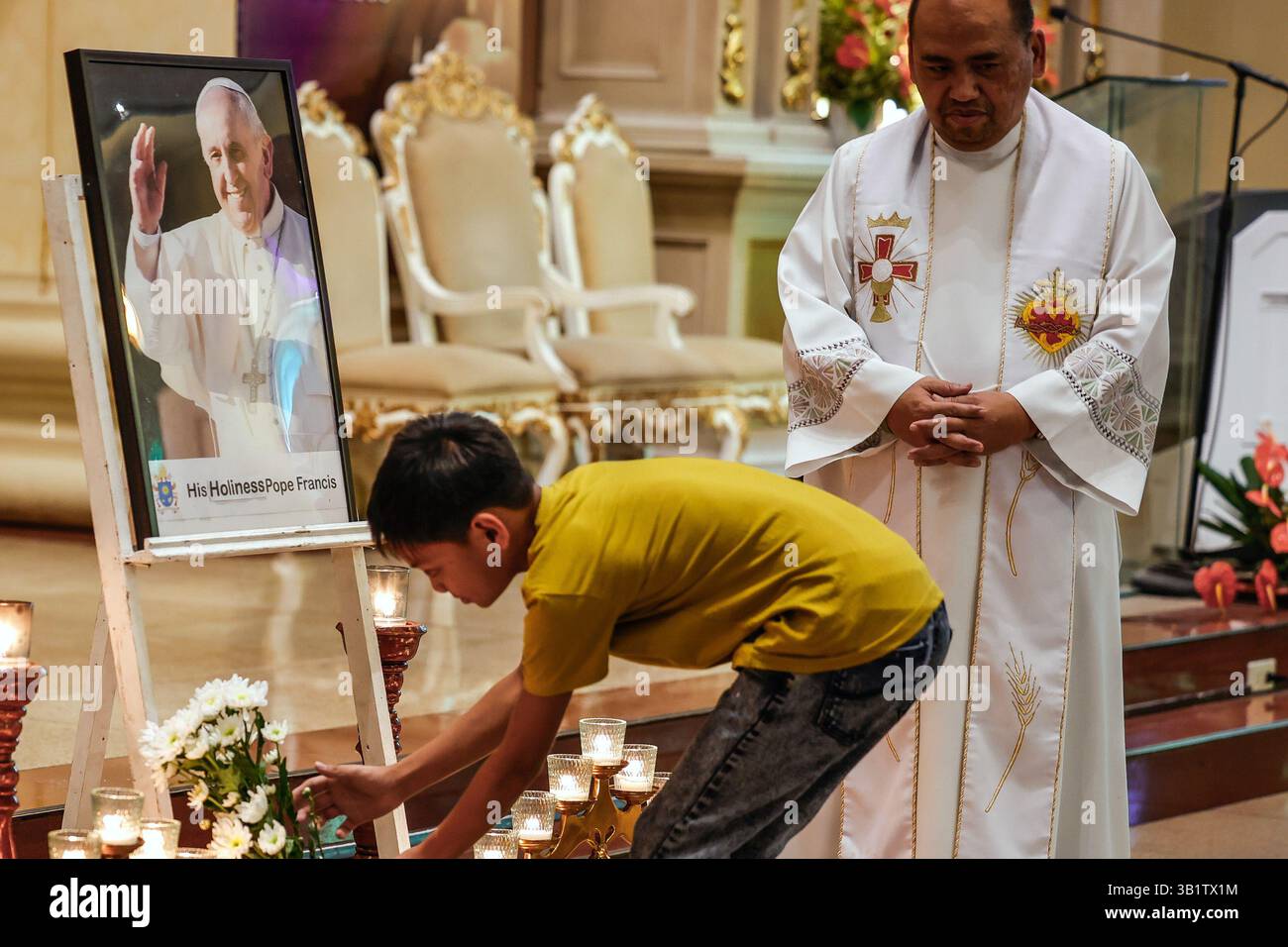 A youth ministry member offers flowers at the portrait of Pope Francis ...