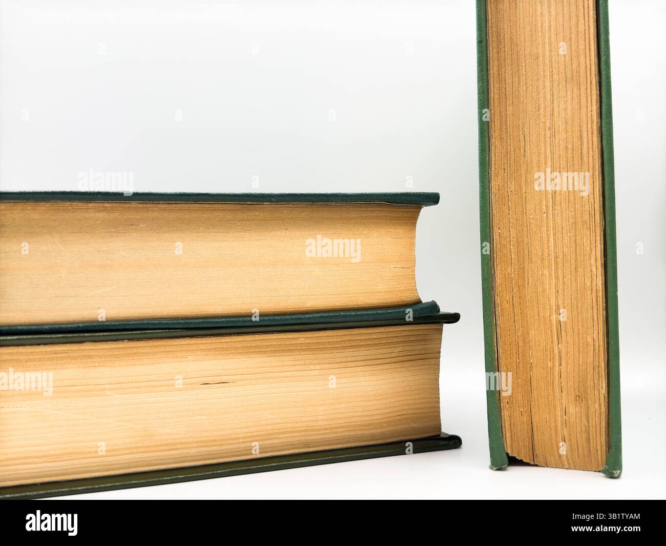 A stack of two old books with yellow tattered pages lying on top of ...