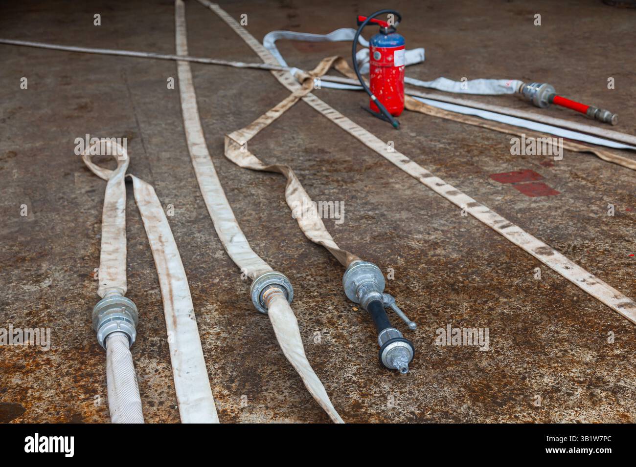 Red fire extinguisher cylinder with unwound fire hoses Stock Photo - Alamy