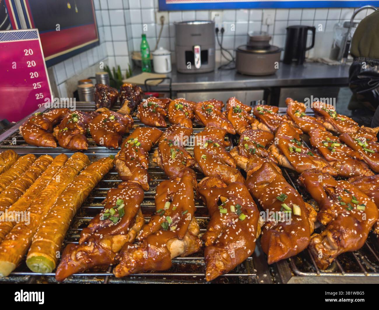 Chinese street food stall. Pig trotters, pork feet on a grill, a ...