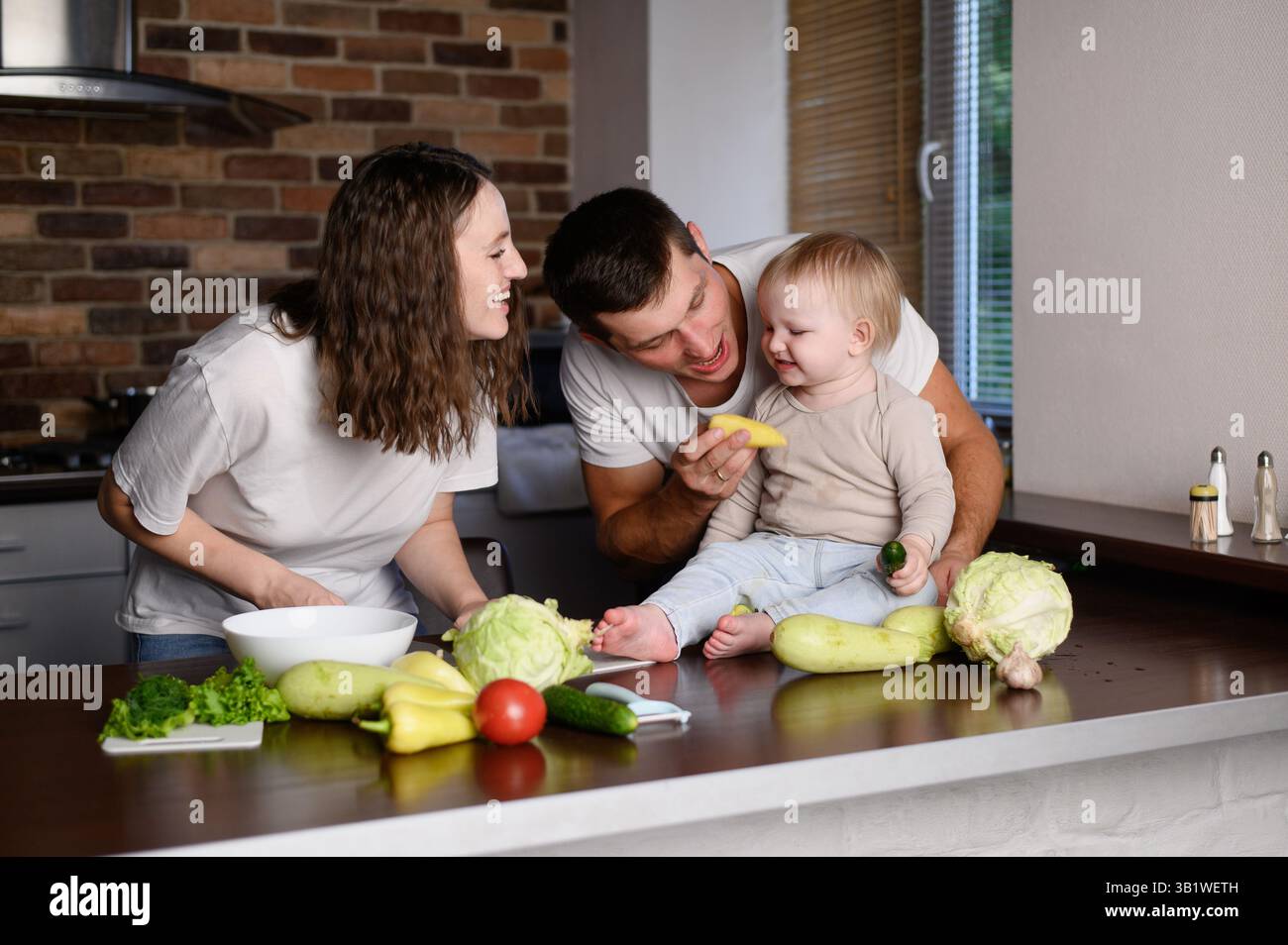 Family with baby busy cooking with fresh vegetables. Mom, dad busy ...