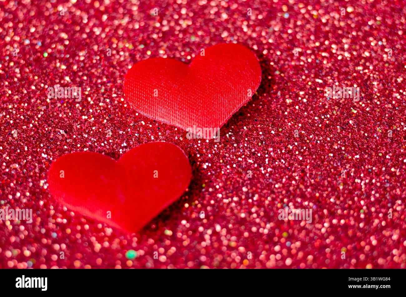 Side view of two tiny red hearts on sparkle red background with ...