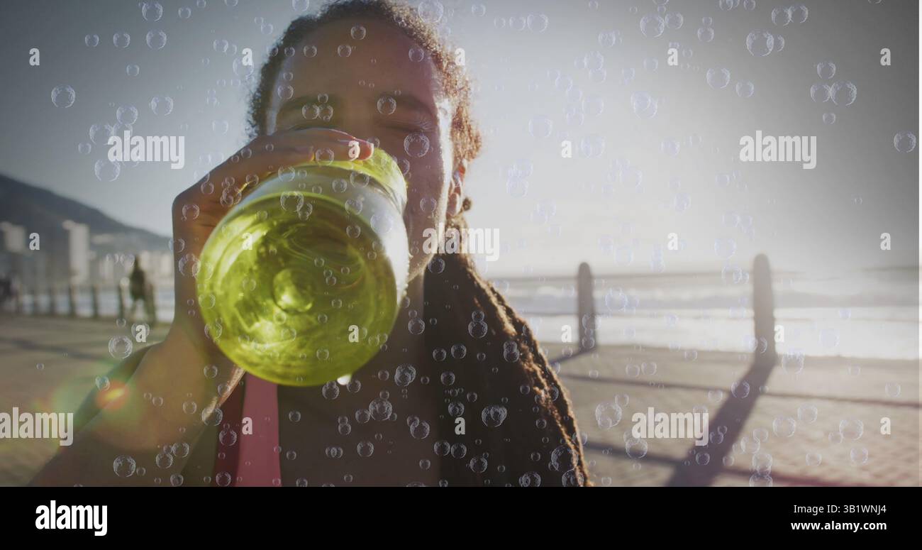 Image of bubbles over woman drinking water on promenade Stock Photo - Alamy