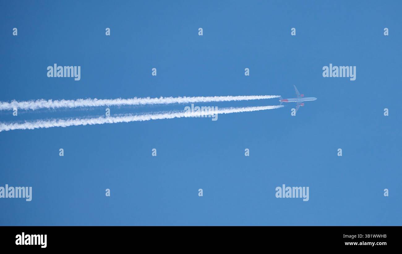 Airplane flying high in the sky with contrails Stock Photo - Alamy