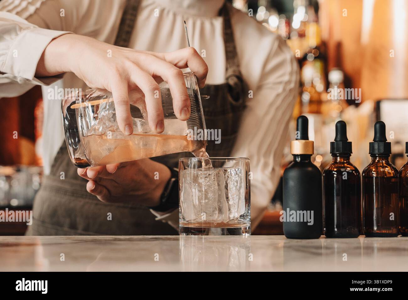 Bartender Pouring Cocktail over Ice at Bar Stock Photo - Alamy