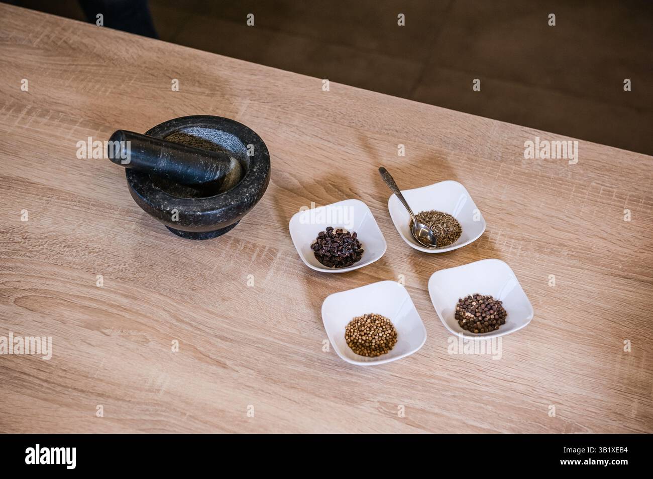 A kitchen marble mortar and spices arranged in bowls during cooking ...
