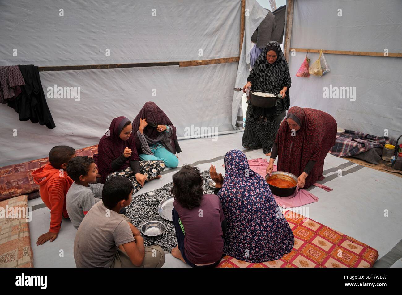 The Al-Najjar family prepares for a meal of peas with rice in their ...