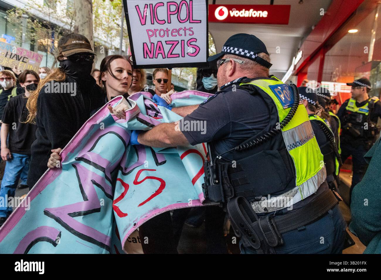 Police push back pro-trans protesters, one holding a placard saying ...