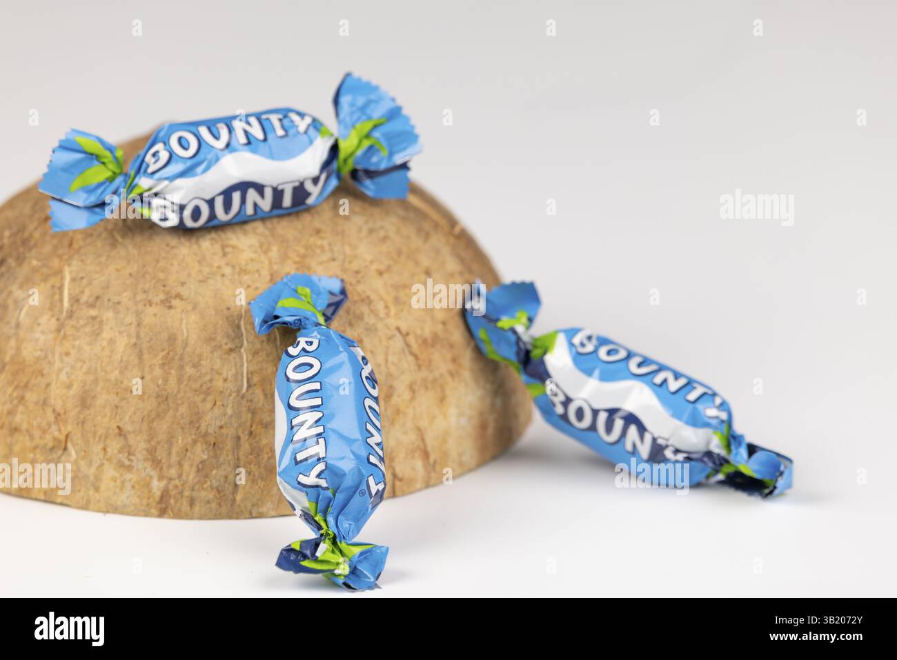 Three Bounty, small chocolate bars on half a coconut on a white ...
