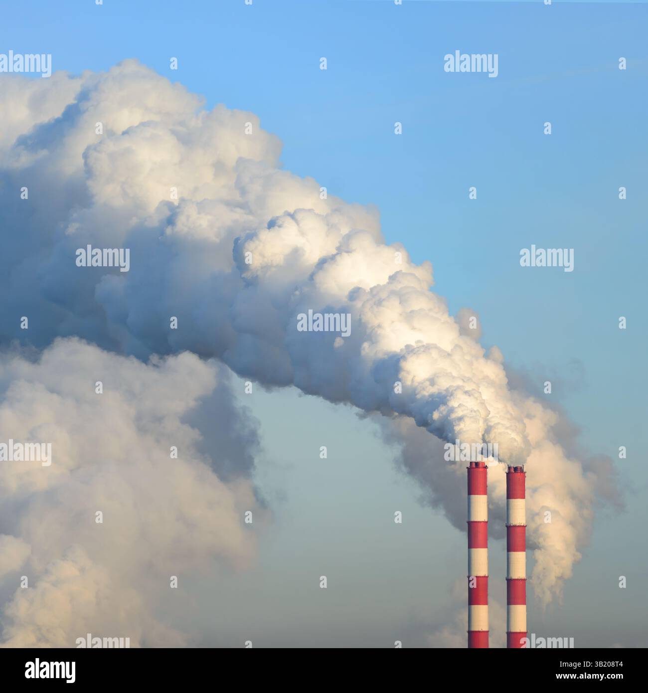Pair of Fuming industrial tubes chimneys smoke heating station blue sky ...