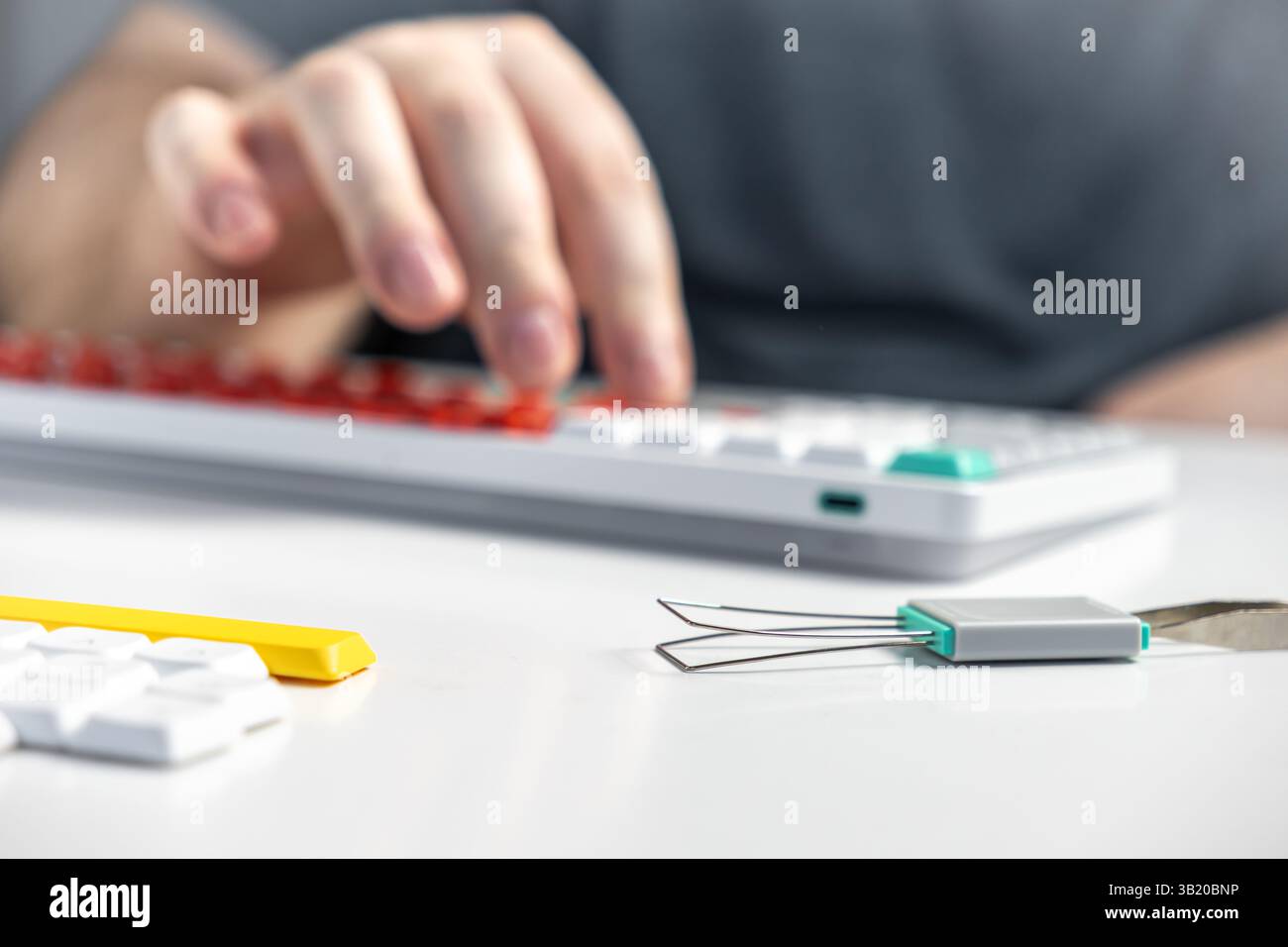 Close up view of hands near a mechanical keyboard with a keycap puller ...