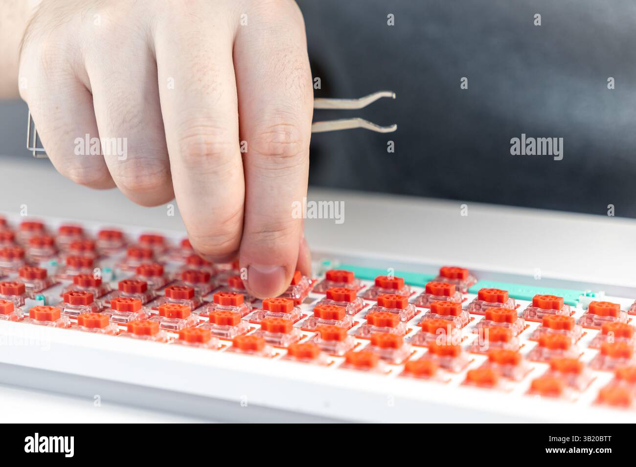 Close-up of a person installing a red mechanical switch using tweezers ...