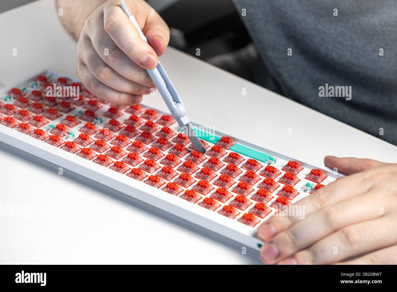 Close-up of hands using a diagnostic probe to inspect red switches on a ...