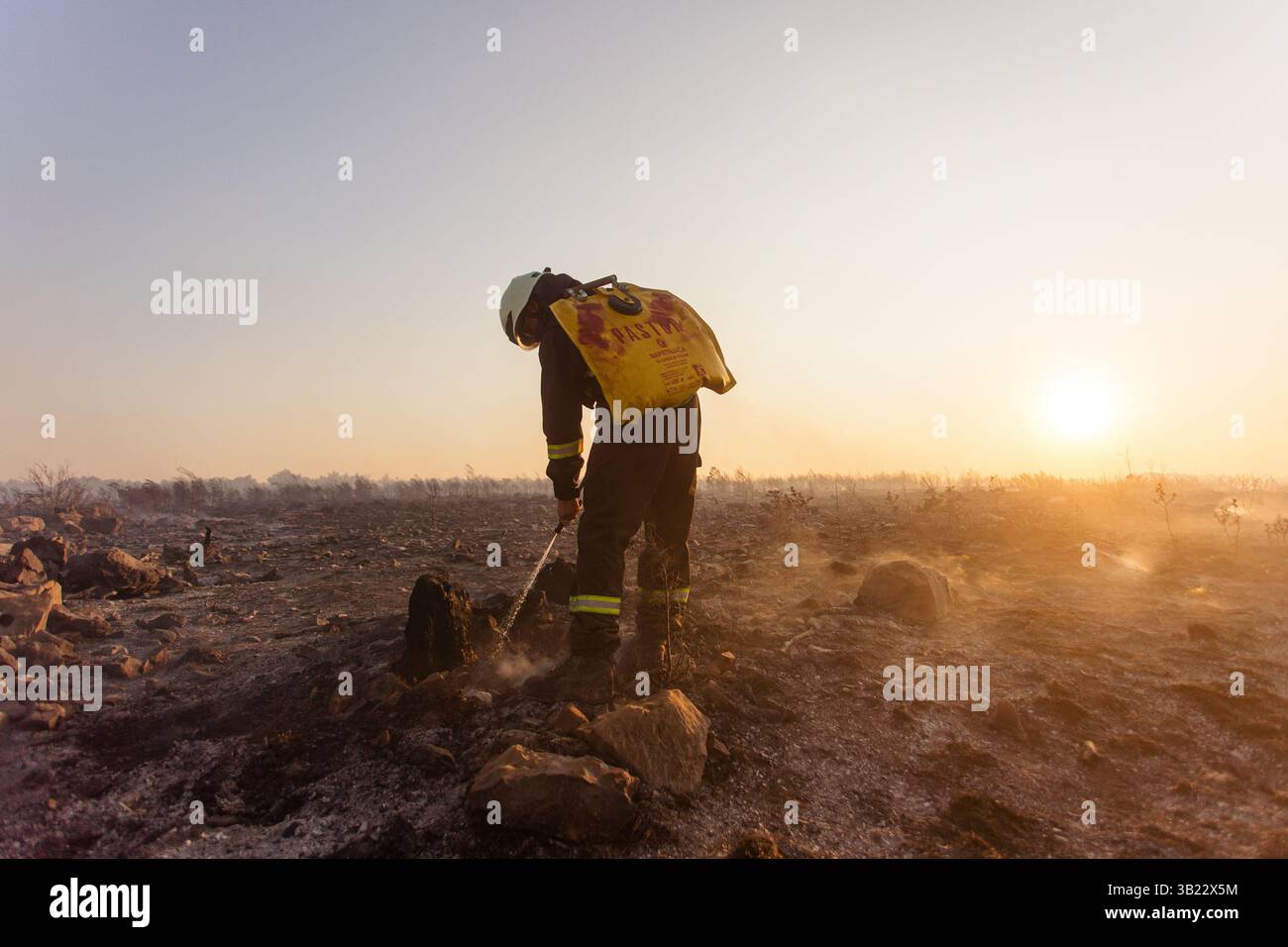 Firefighter carrying water bag on back, battling wildfire in rugged ...