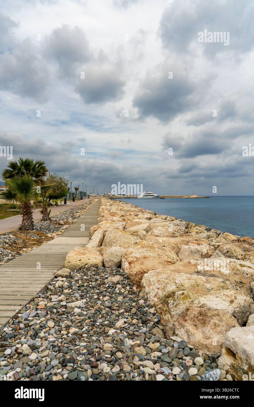 Scenic coastal walkway in Latchi, Cyprus, featuring pale stone paving ...