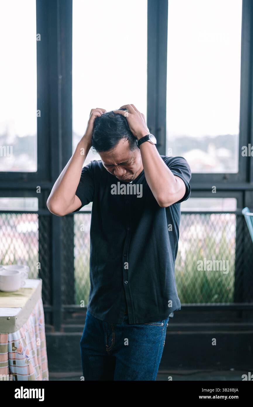 A stressed man pulls his hair. Depicts anxiety and pressure. Indoor ...