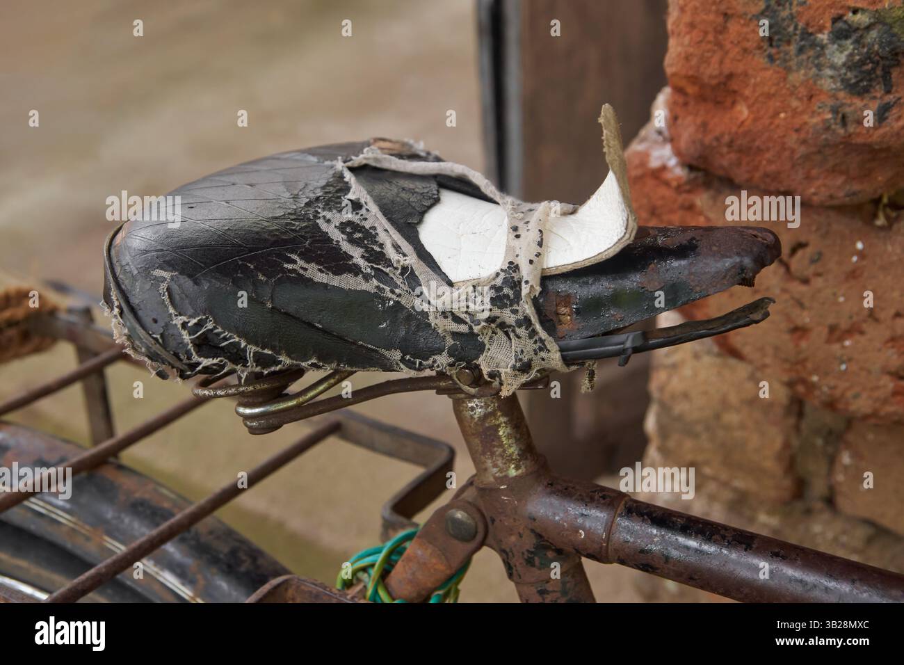 close-up of worn out and damaged black bicycle seat, frame is partly ...