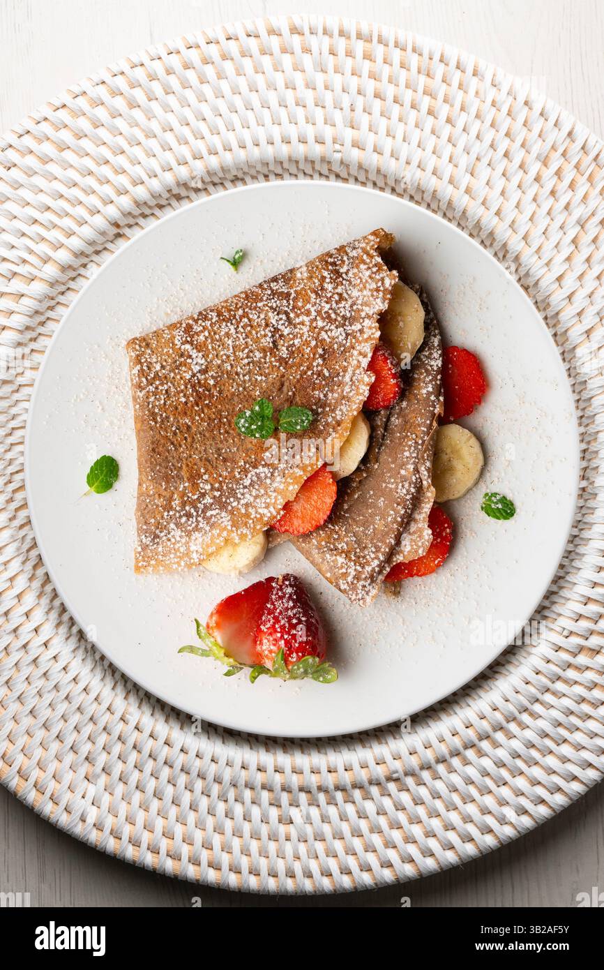 Chocolate crepes filled with strawberry and fresh banana. Top view ...