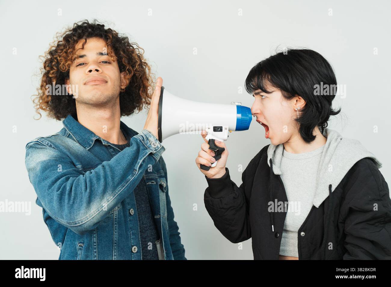 A young woman shouting at her husband or boyfriend with a megaphone ...