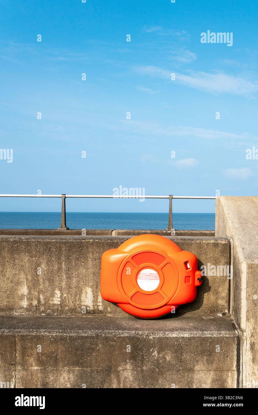 Orange life buoy container attached to concrete wall Stock Photo - Alamy