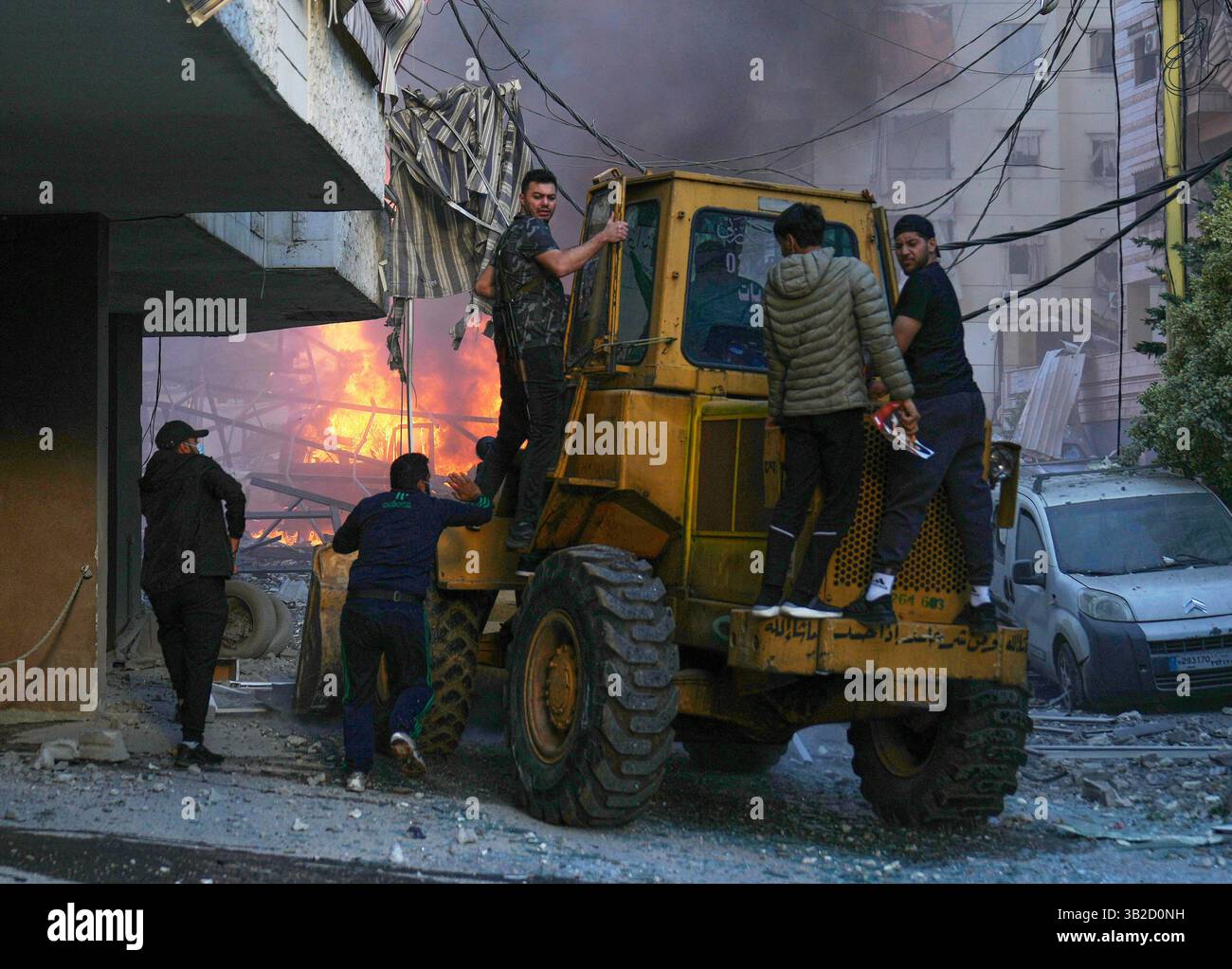 A bulldozer arrive to remove debris as flames rise from a metal tent ...