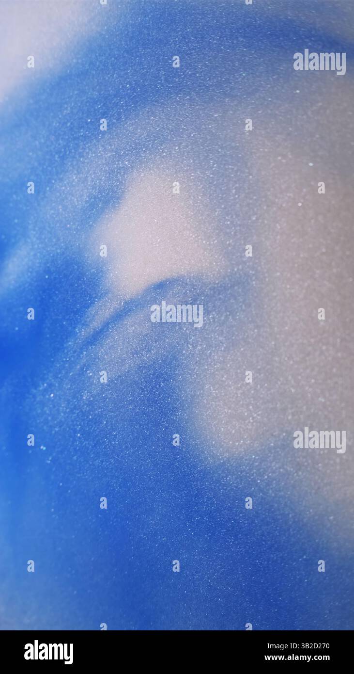 Ink mix flow. Glitter fluid spill. Defocused blue white color paint in ...