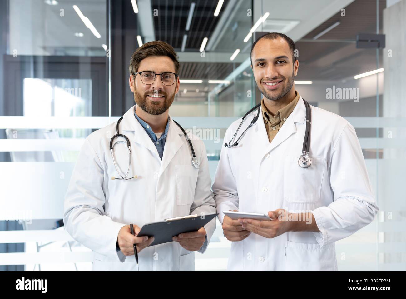 Two doctors in white coats stand side by side, smiling confidently in a ...