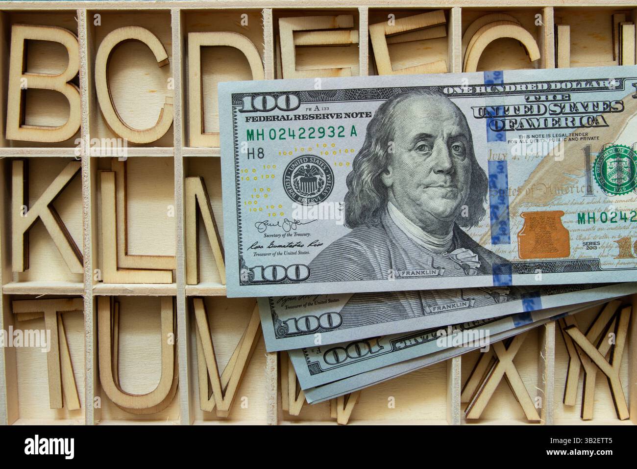 Wooden alphabet letters in cells and dollar bills, education and ...
