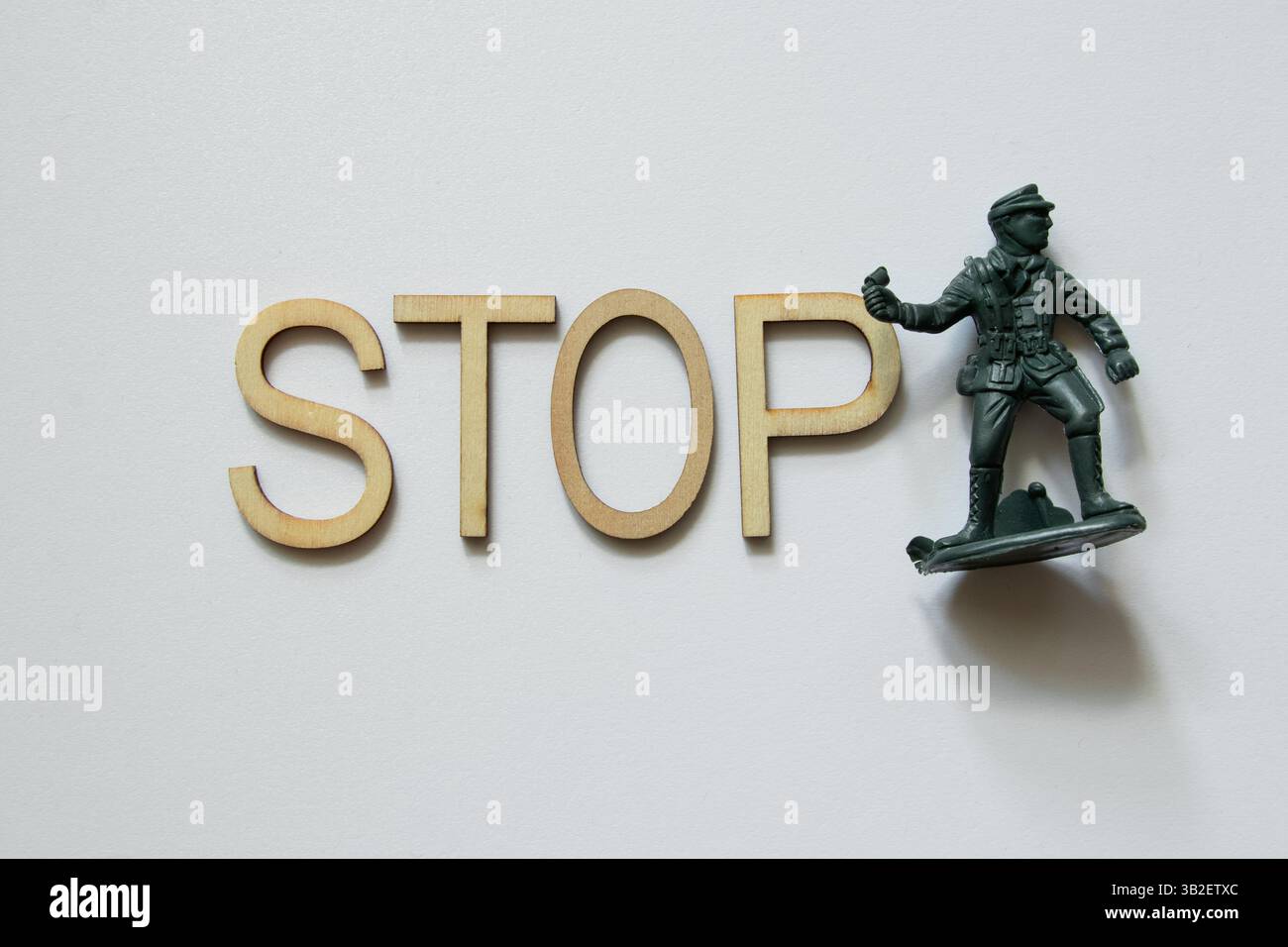 Word stop made of wooden letters and green plastic soldier on white ...