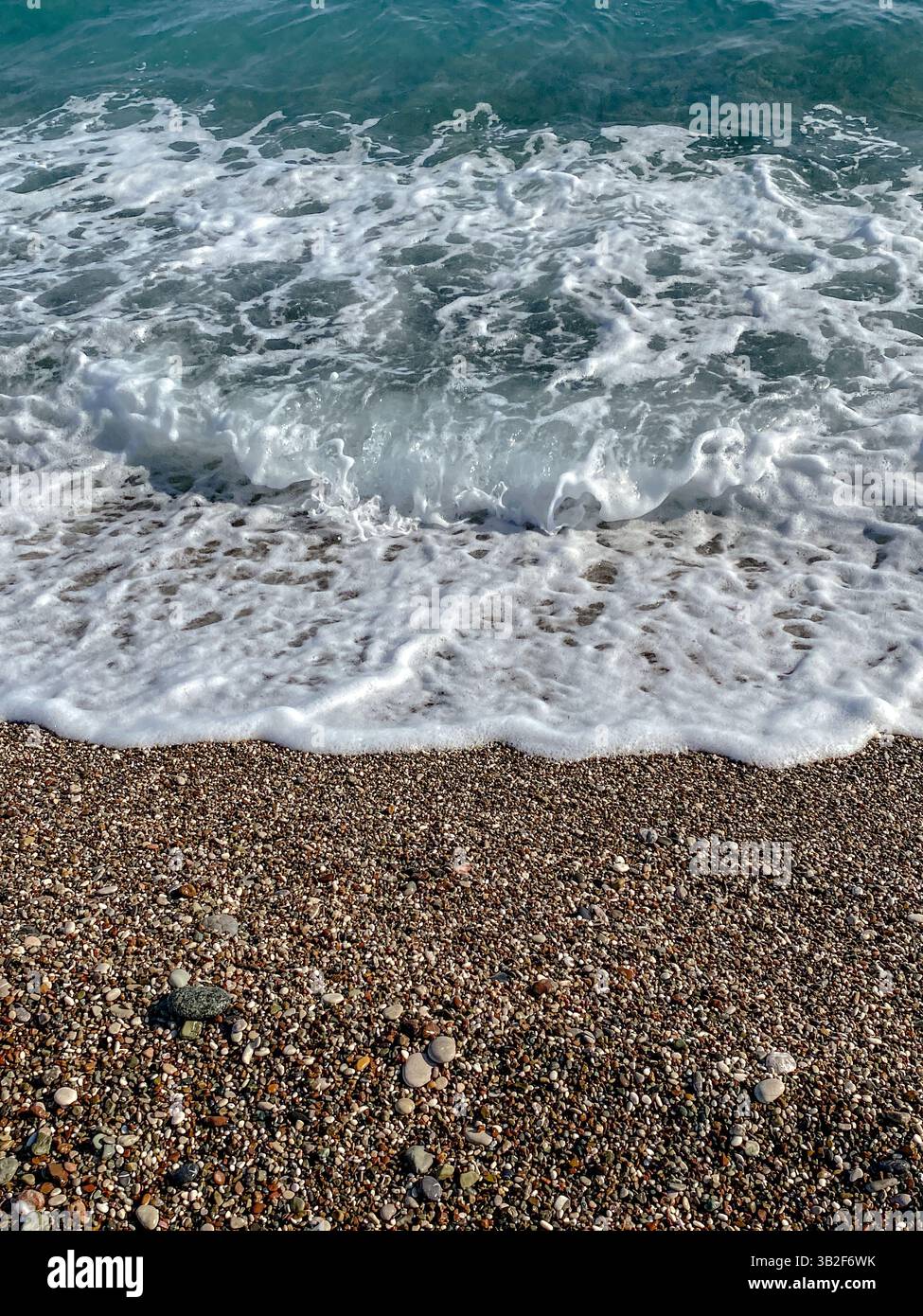 Sea wave with white foam washing over a pebble beach in Antalya, Turkey ...