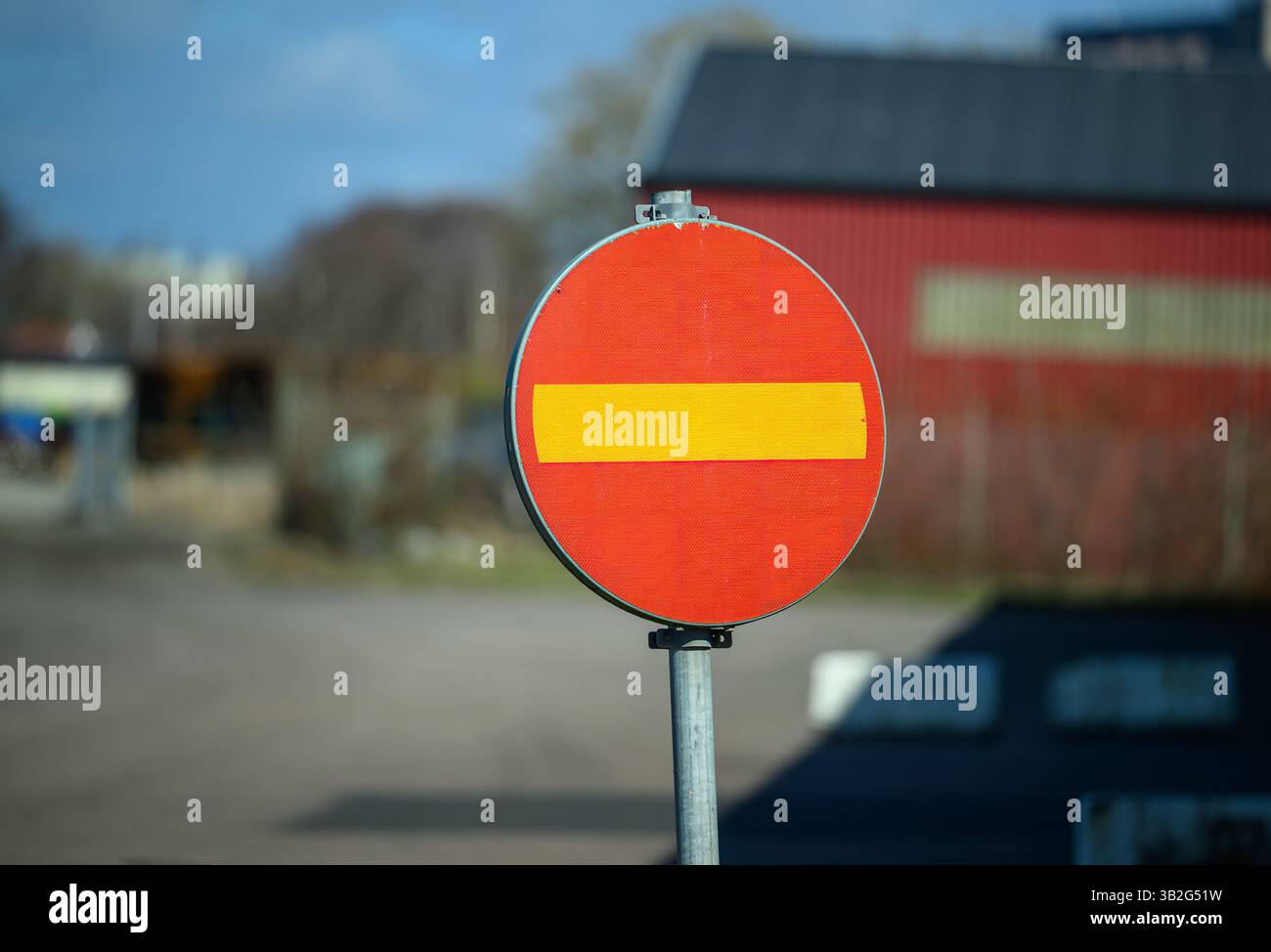 A circular no entry sign stands prominently in a parking area under a ...