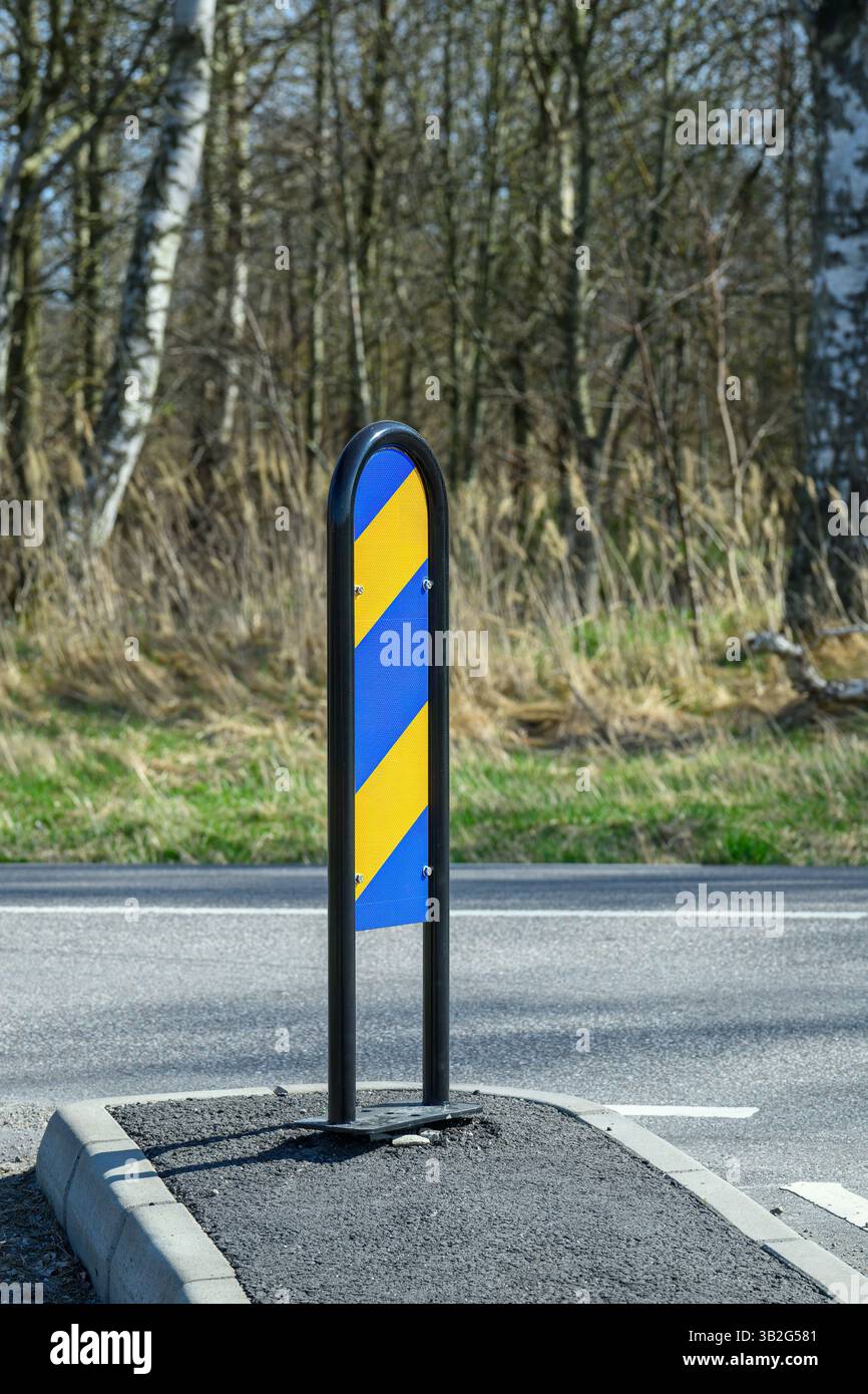 A vertical traffic sign featuring bold blue and yellow stripes stands ...