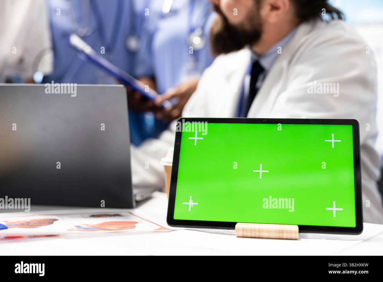 Doctors and nurses review radiography scans with a green screen on desk, discussing potential ...